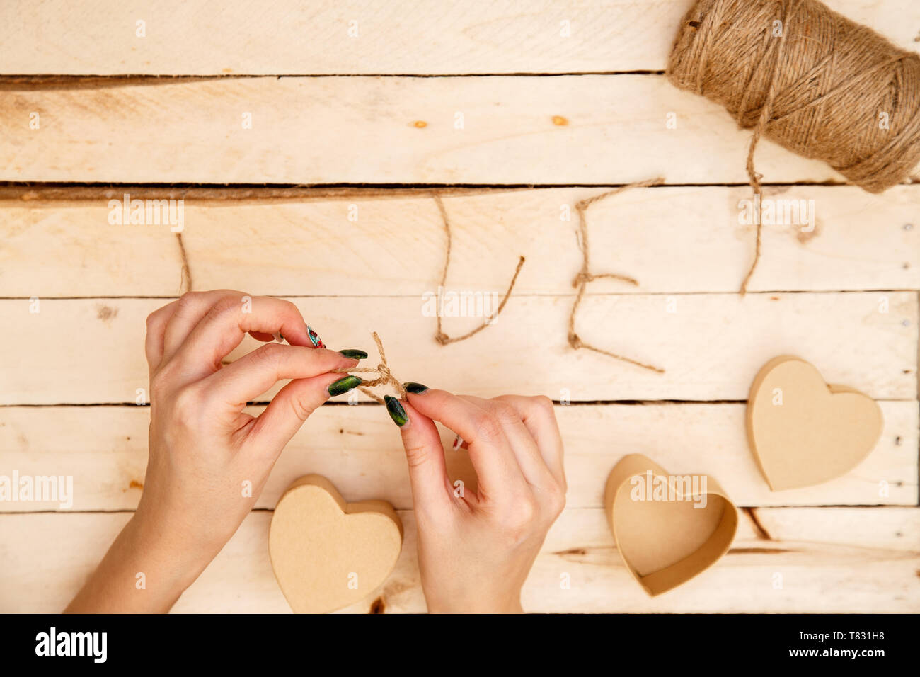 women's hands spread hearts and the word love of threads on a light ...
