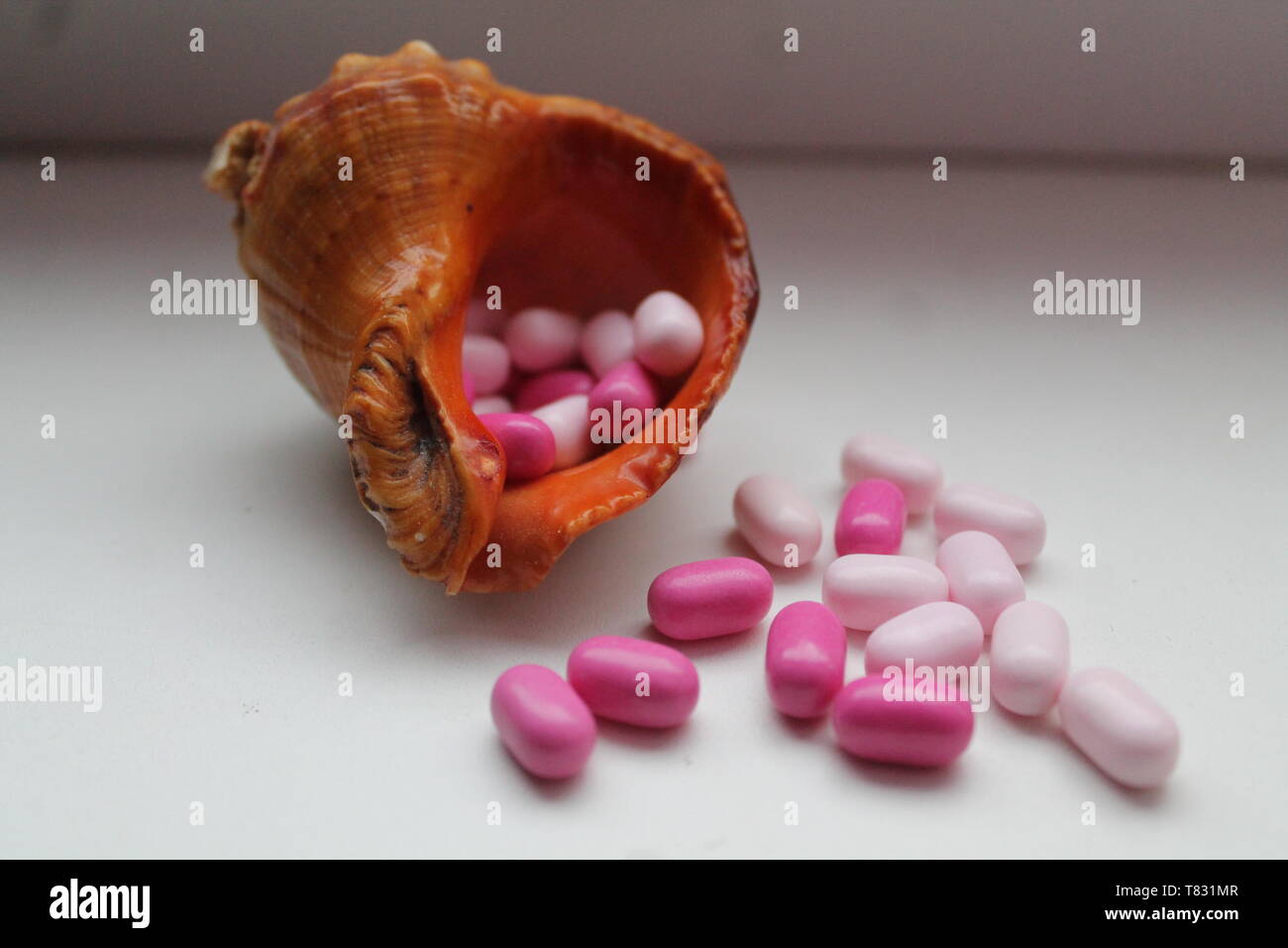 smooth bright pink candy drops look like medicine pills lay with sea ...