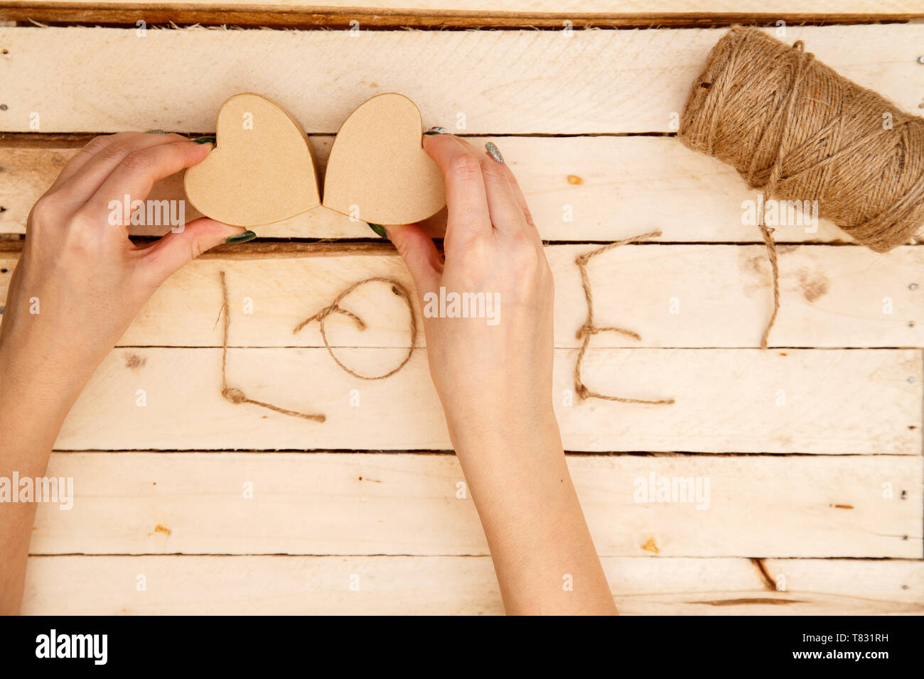 women's hands spread hearts and the word love of threads on a light ...