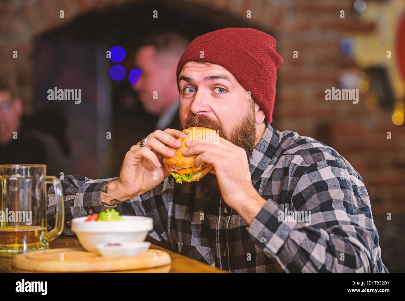 Brutal hipster bearded man sit at bar counter. High calorie food. Cheat ...