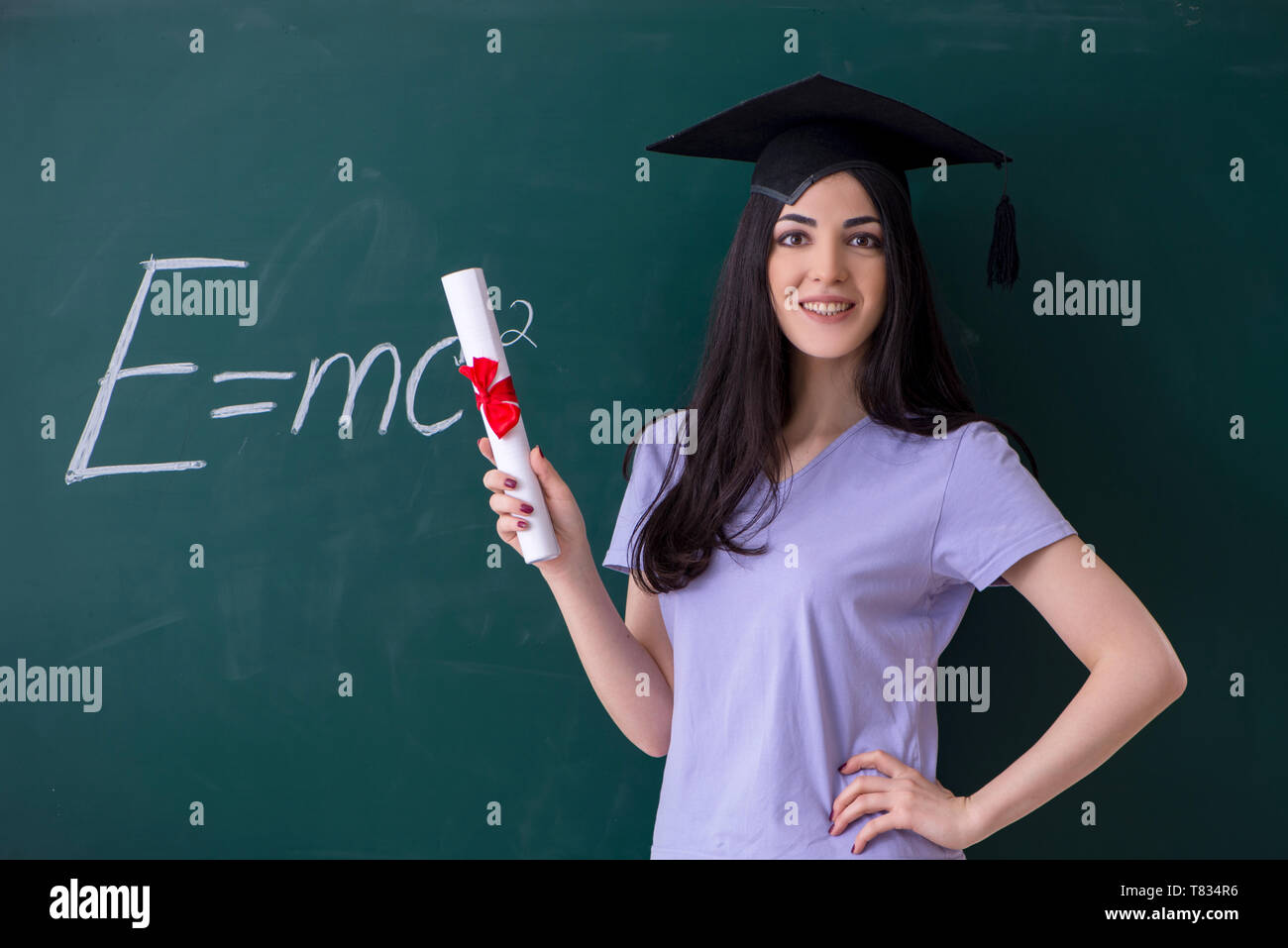 Female graduate student in front of green board Stock Photo - Alamy