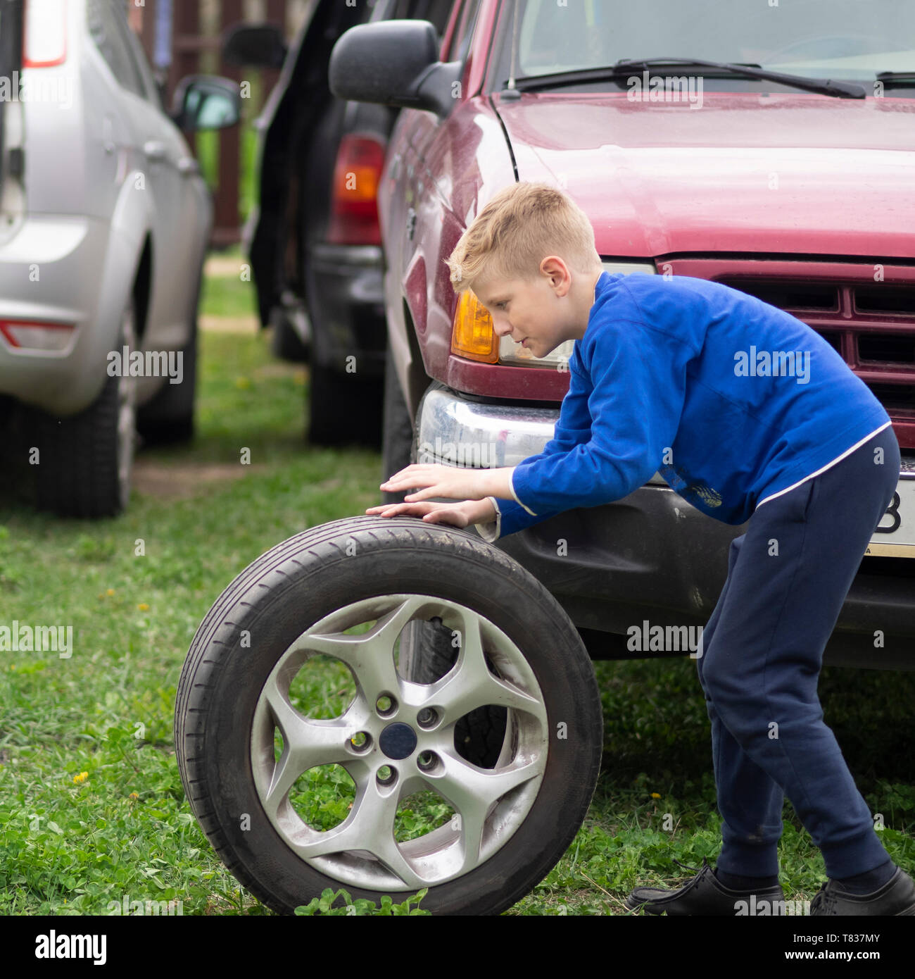 caucasian boy is rolling a car wheel Stock Photo - Alamy