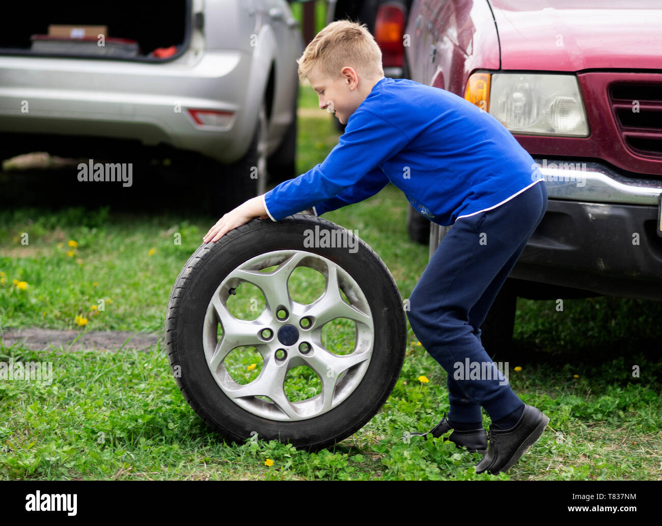 caucasian boy is rolling a car wheel Stock Photo - Alamy