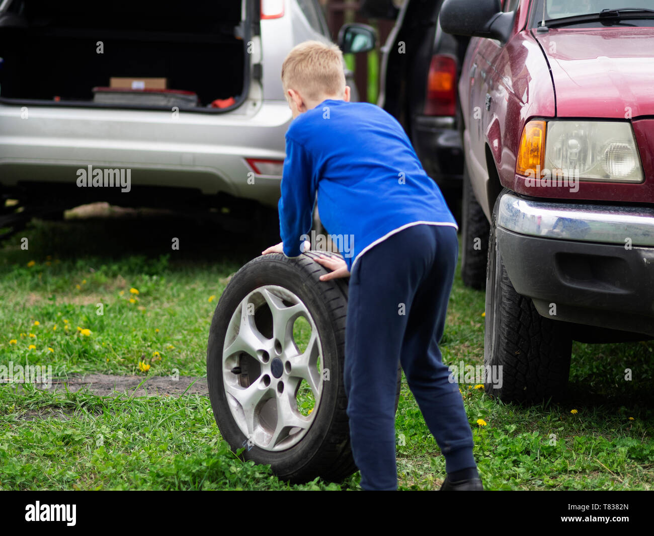 caucasian boy is rolling a car wheel Stock Photo - Alamy