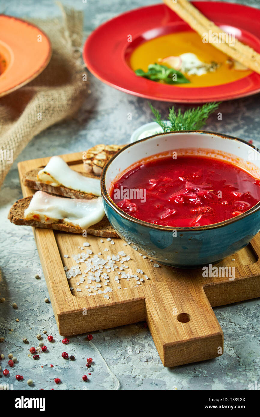 Red beet soup, black bread with bacon on the board. Beautiful serving ...