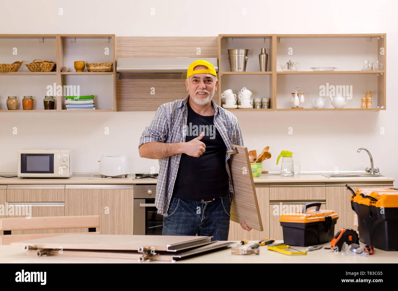 Aged contractor repairman working in the kitchen Stock Photo - Alamy