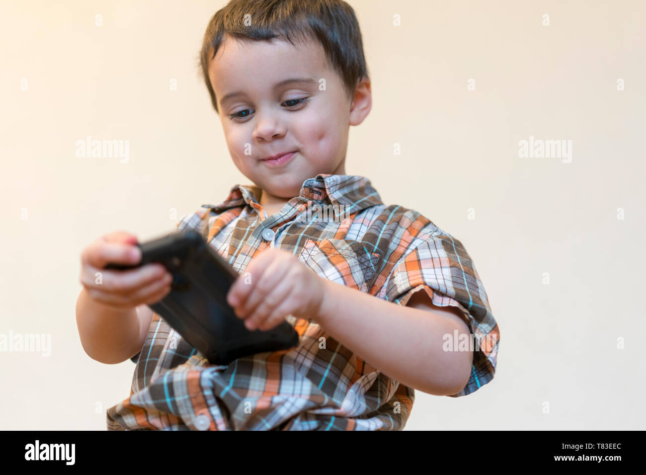 Portrait of a smiling little boy holding mobile phone isolated over ...