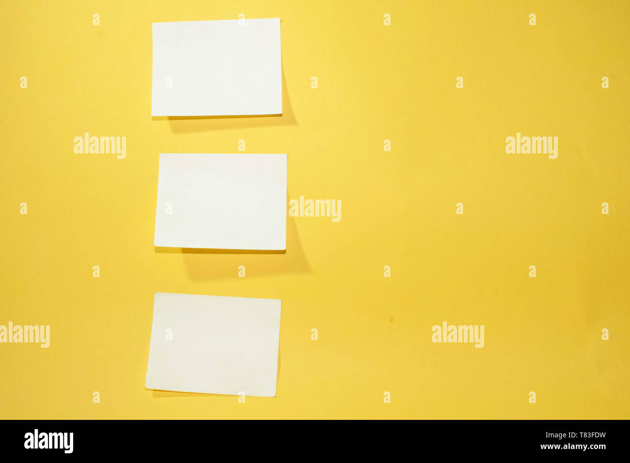 Three blank yellow sticky notes arranged vertically on an orange ...