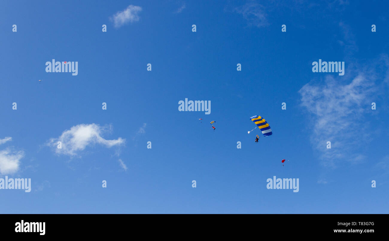 Silhouette of sky divers flies back to the ground after a tandem ...