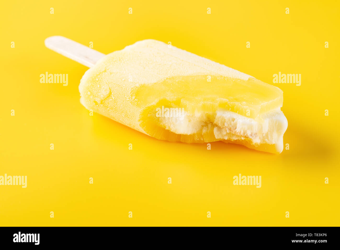 side view yellow popsicle with bites on a yellow background Stock Photo ...