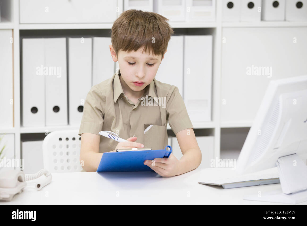 Junior school student does his homework. A boy with a pen in his hands ...