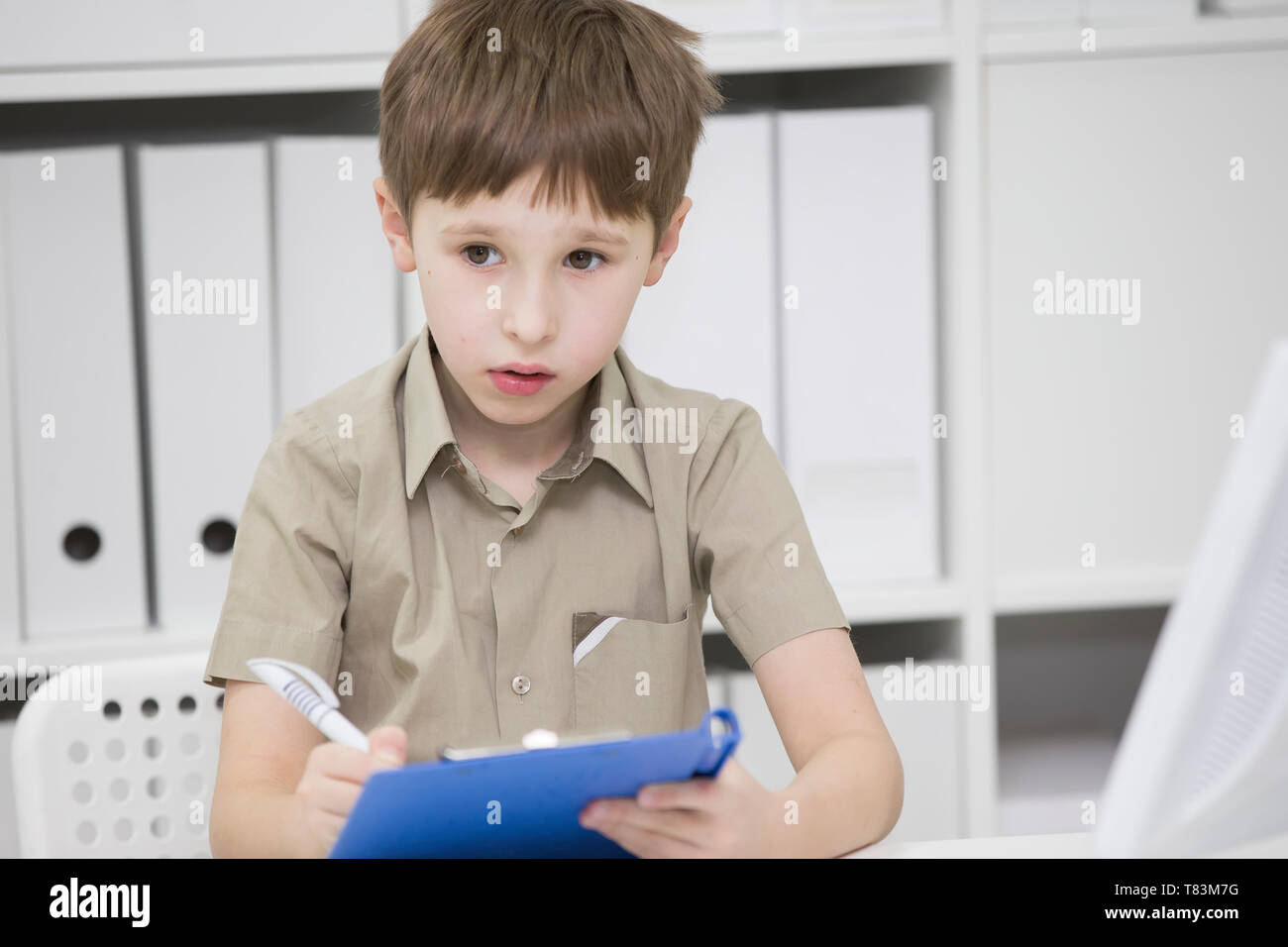 Junior school student does his homework. A boy with a pen in his hands ...