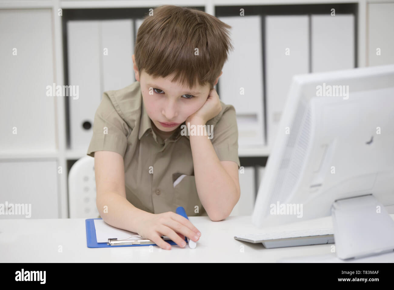 Sad schoolboy does homework. Upset boy behind desk with pen and ...