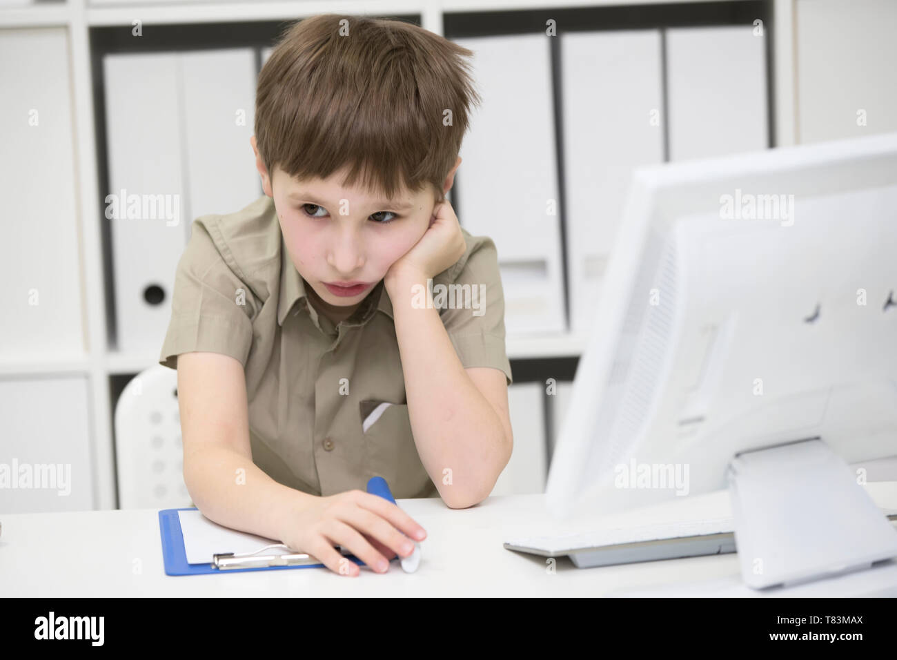 Sad schoolboy does homework. Upset boy behind desk with pen and ...
