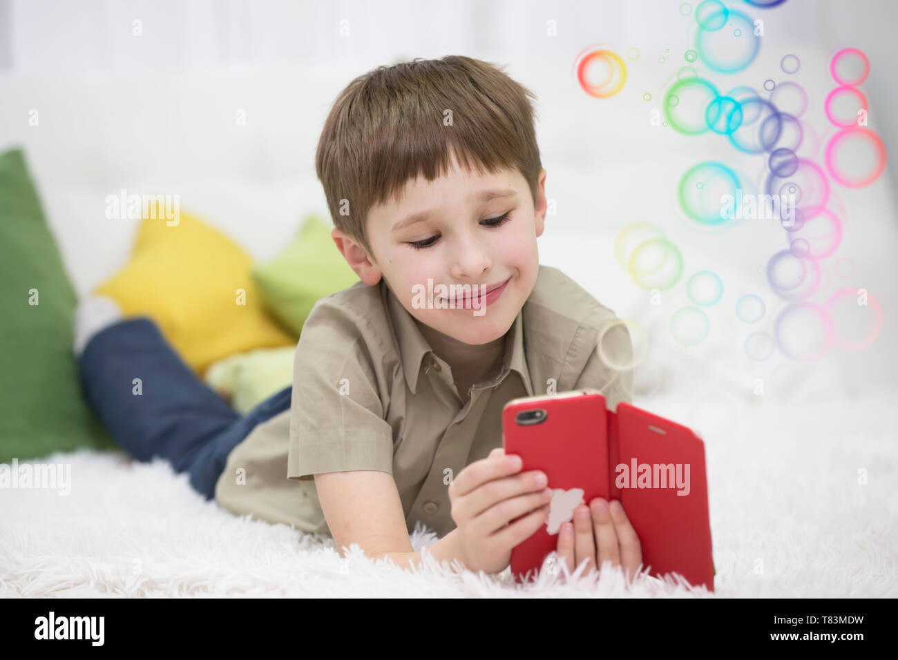 Child with a mobile phone. Schoolboy with a smartphone lying on the bed ...