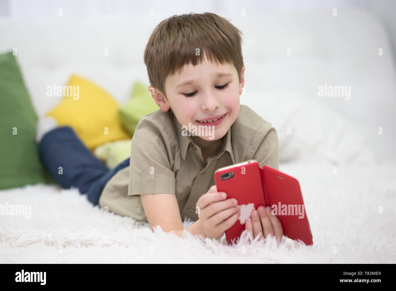 Child with a mobile phone. Schoolboy with a smartphone lying on the bed ...
