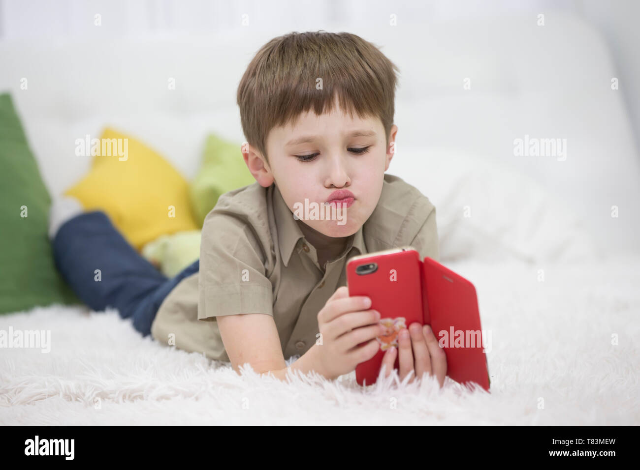 Child with a mobile phone. Schoolboy with a smartphone lying on the bed ...