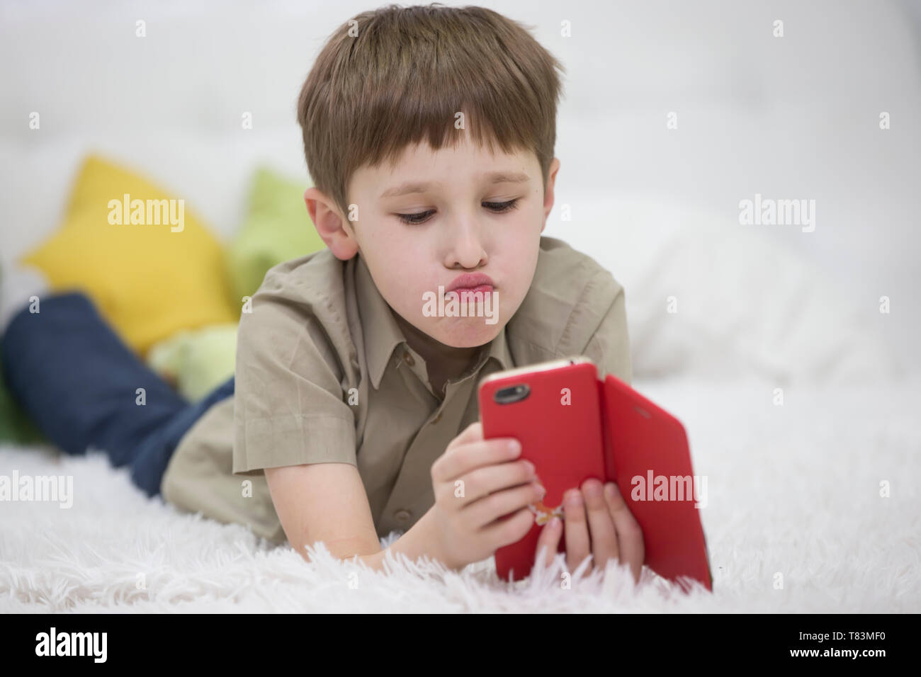 Child with a mobile phone. Schoolboy with a smartphone lying on the bed ...