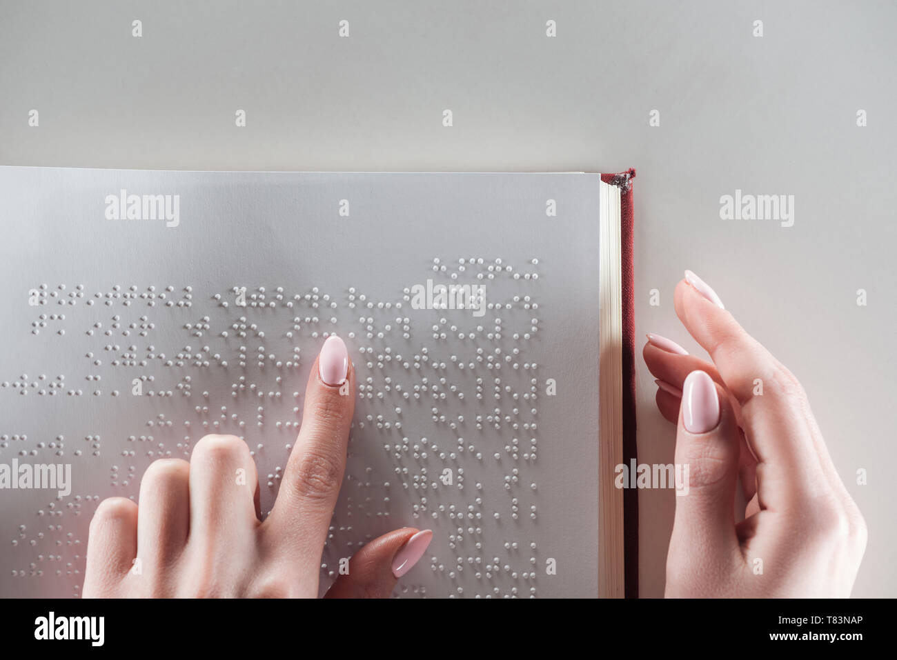 top view of young woman reading braille text on white paper Stock Photo ...