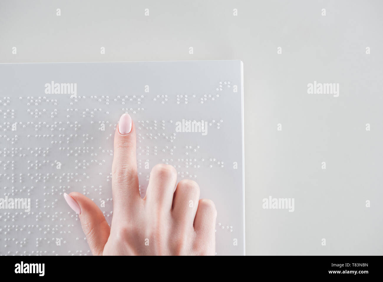 top view of young woman reading braille text on white paper with copy ...