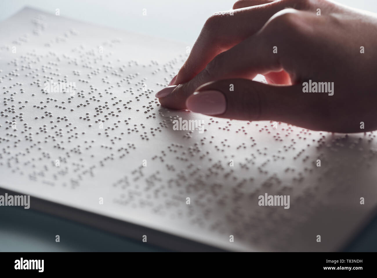 cropped view of young woman reading braille text on white paper Stock ...