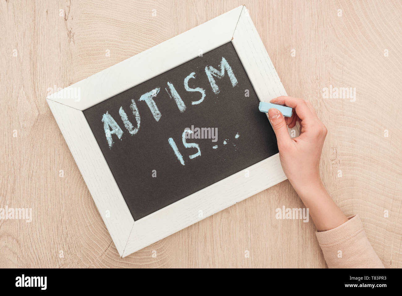 partial view of woman writing autism is lettering with chalk on ...