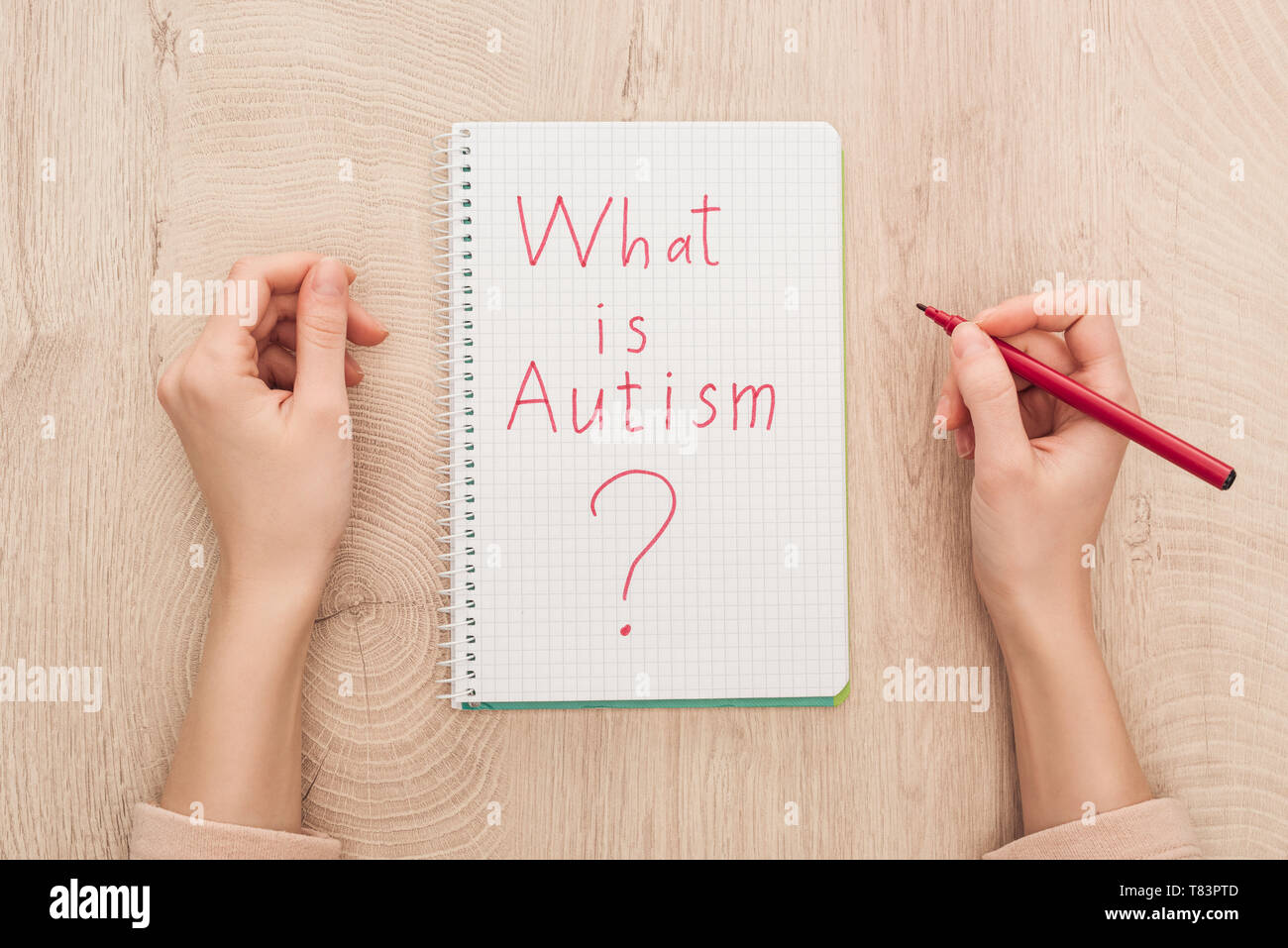 cropped view of woman holding marker near notebook with what is autism ...