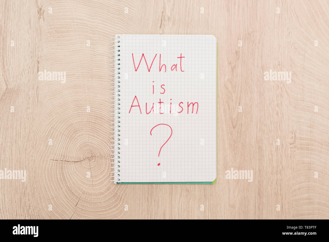top view of red what is autism question written in notebook on wooden ...
