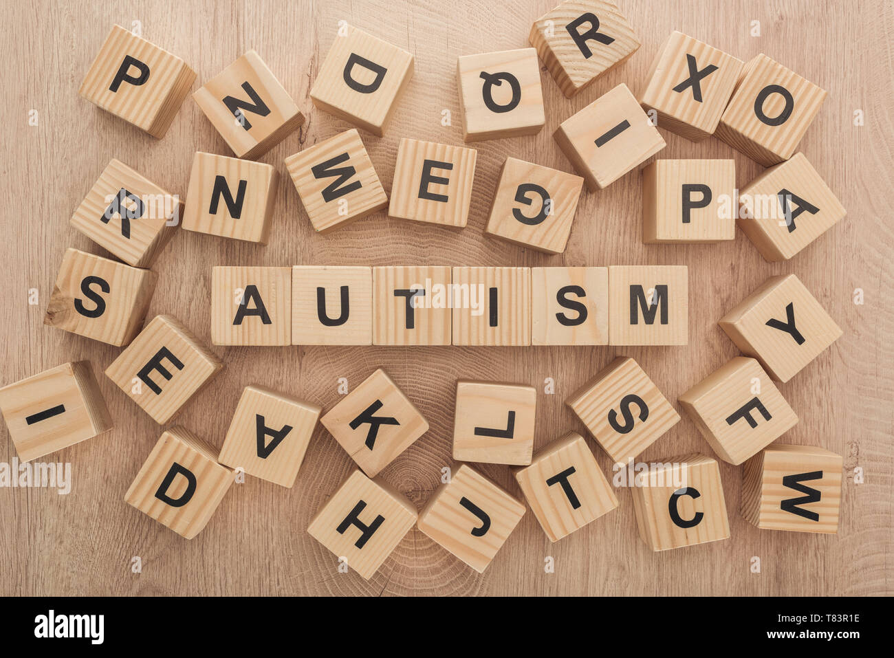 top view of autism lettering made of wooden blocks among another ...