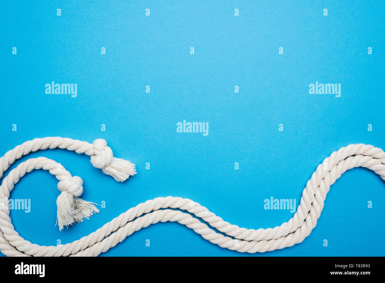 white long waved ropes with knots isolated on blue Stock Photo - Alamy