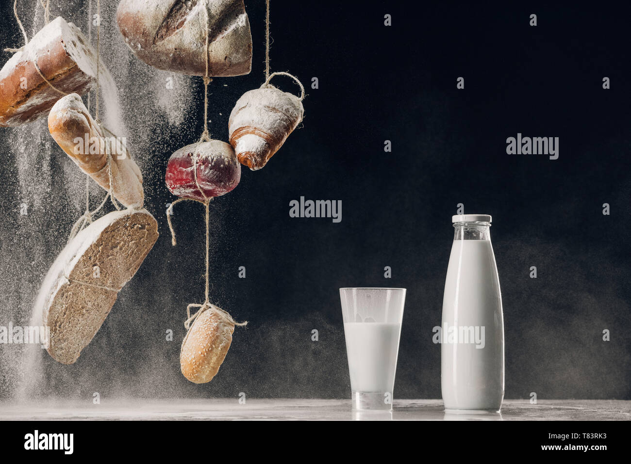 flour falling at homemade bread hanging on ropes near splashing milk on ...