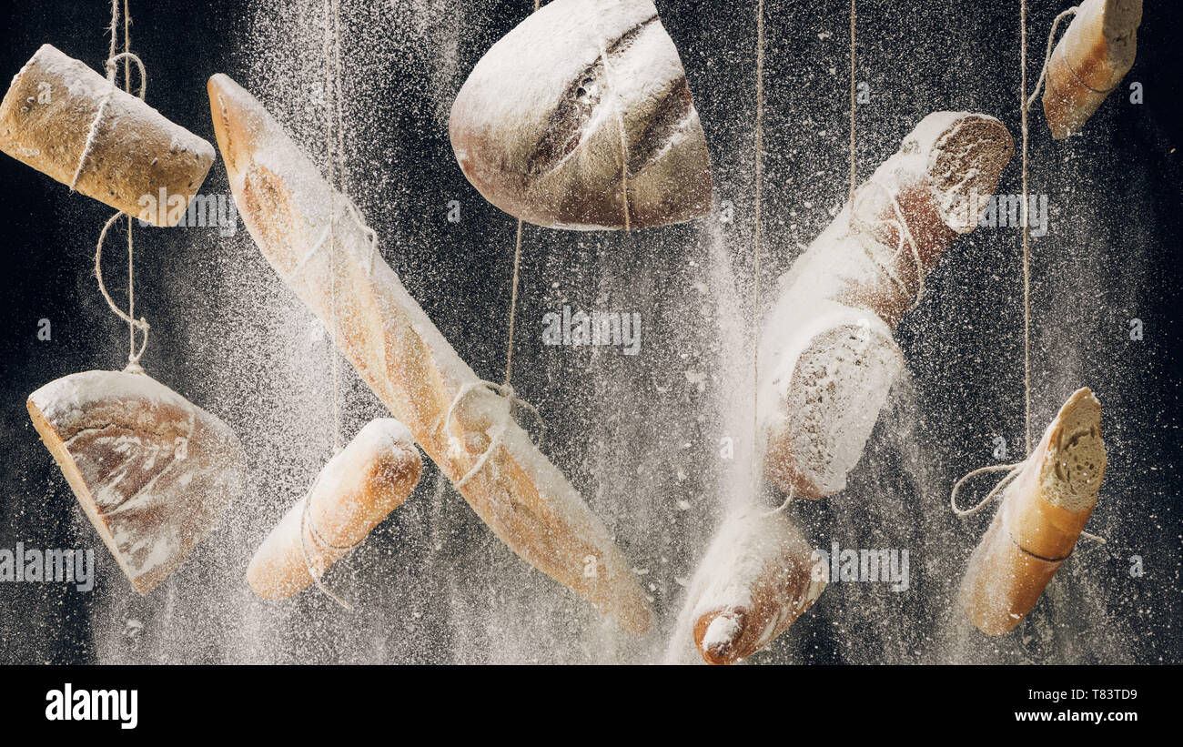 flour falling at baked bread, baguettes and croissant hanging on ropes ...