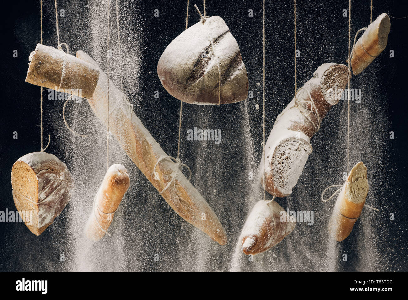 flour falling at bread, baguettes and croissant hanging on ropes on ...