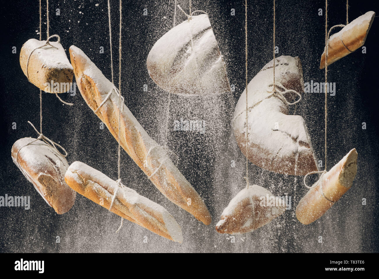 white flour falling at fresh baked bread, baguettes and croissant ...