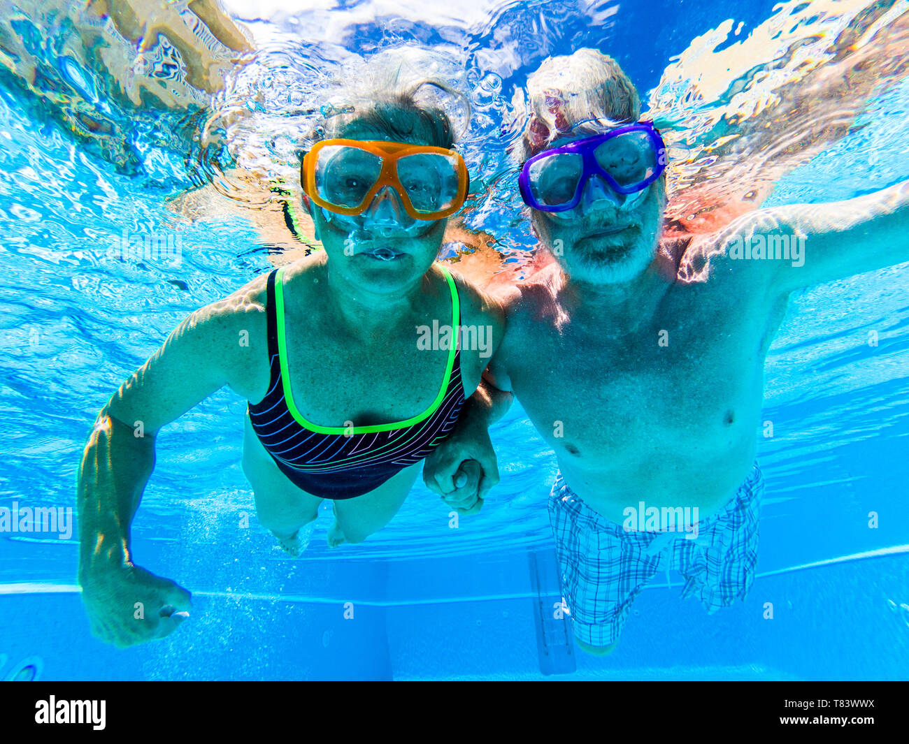 Adult people senior couple have fun swimmin in the pool underwater with ...