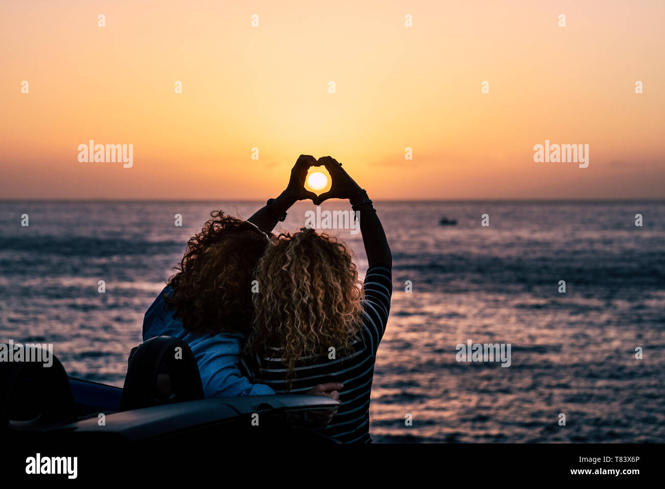 Romantic friendship people concept with two curly lady viewed from back ...