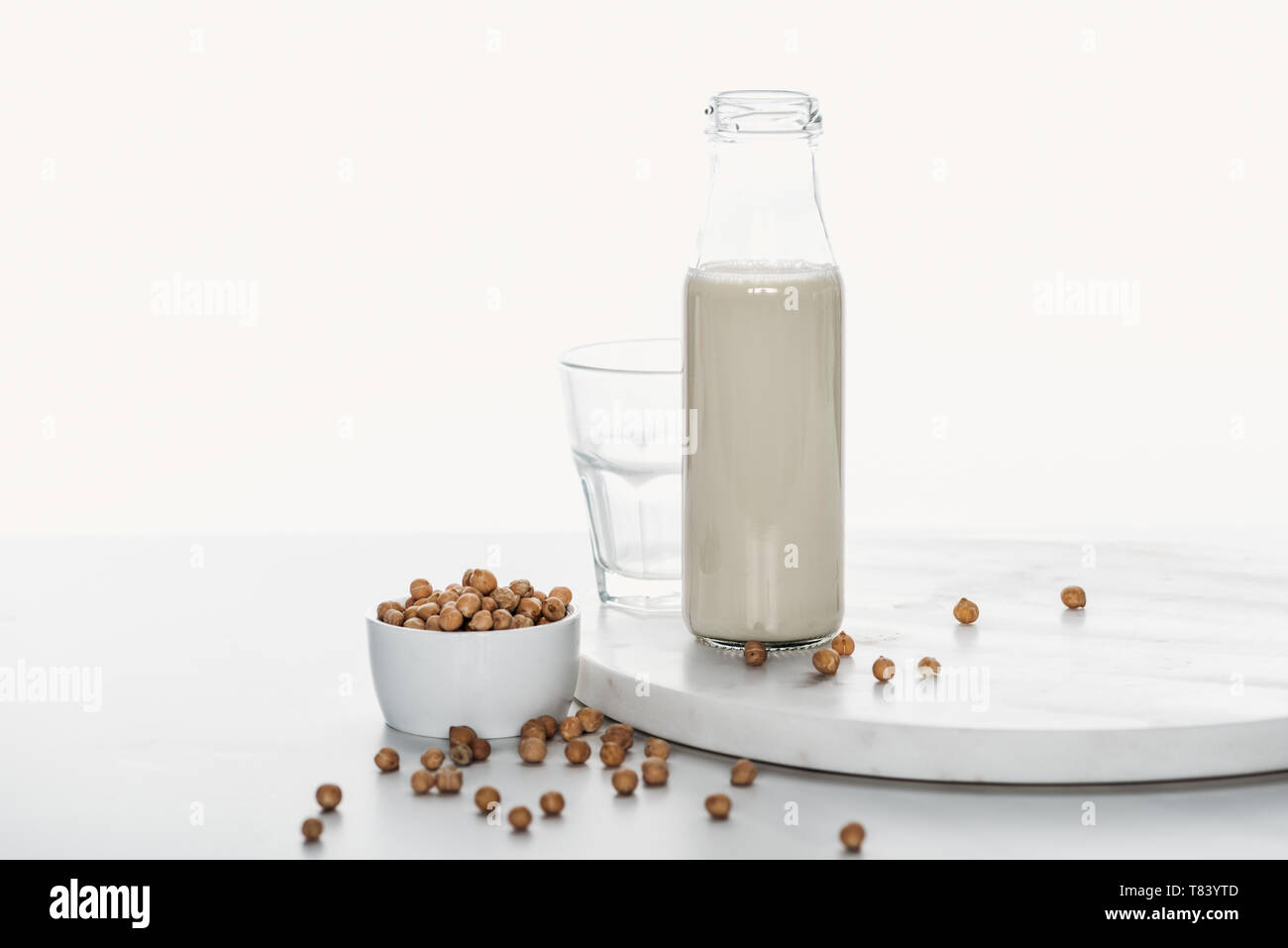 chickpea milk in bottle near chickpea in bowl and empty glass isolated ...