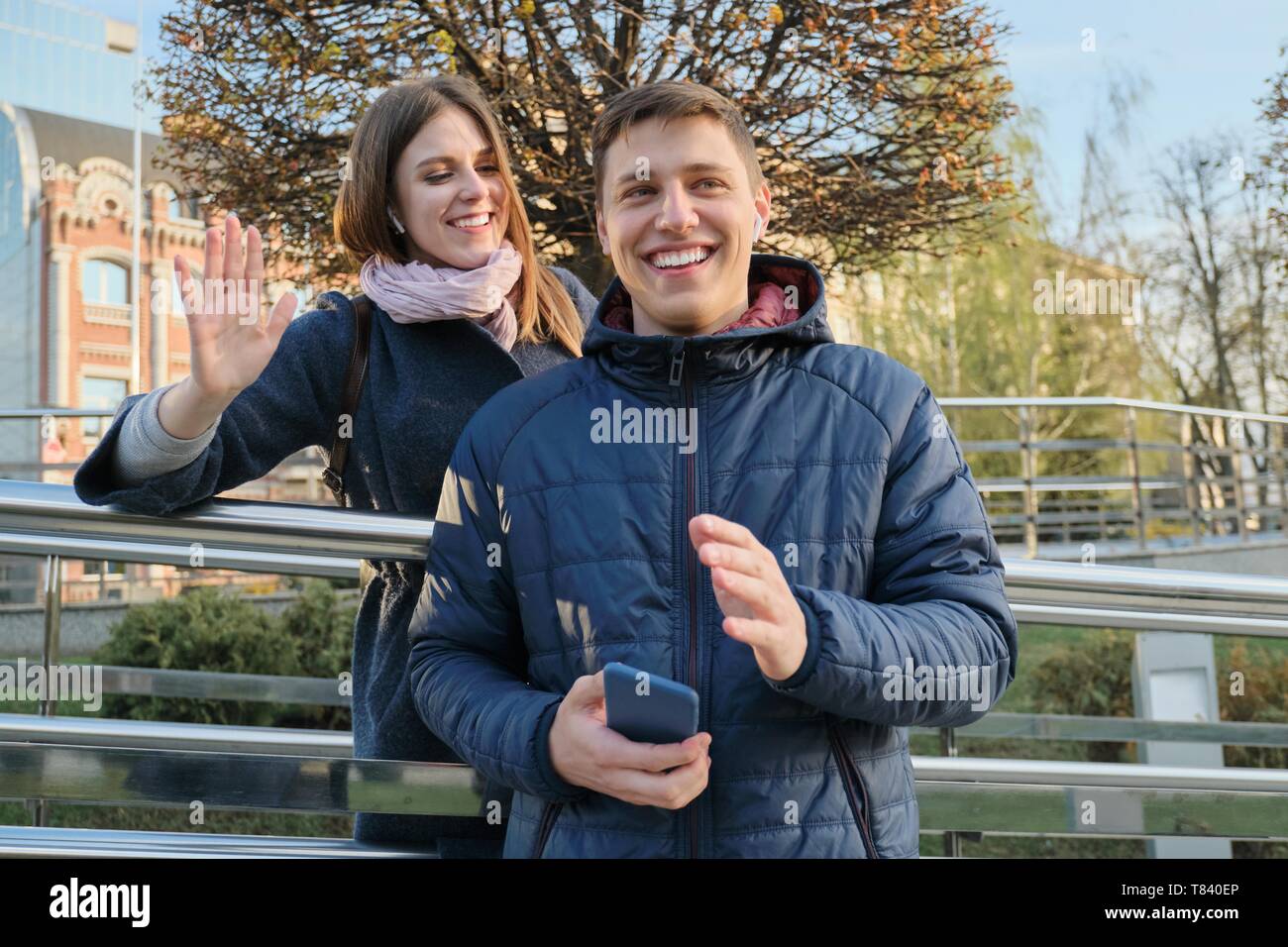 Happy young couple of students gives high five, spring city background ...