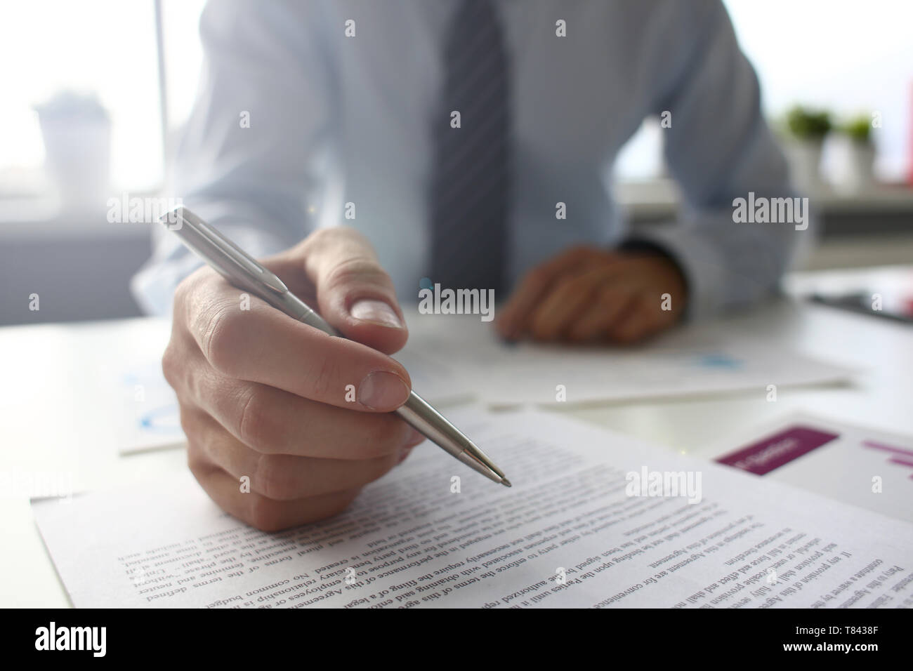 Hand of businessman in suit filling and signing with silver pen ...