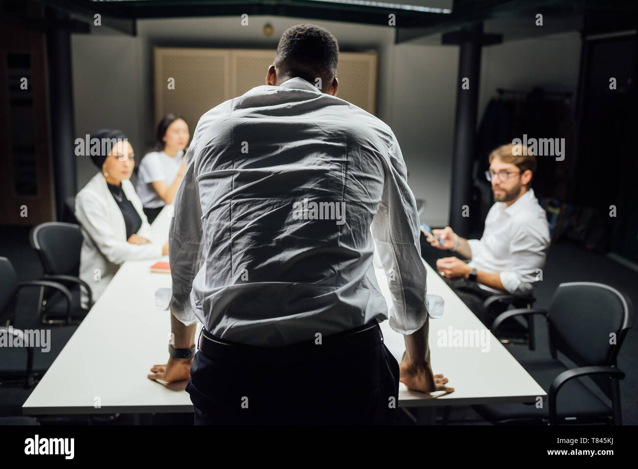 Businessman in front of team at conference table meeting, rear view ...