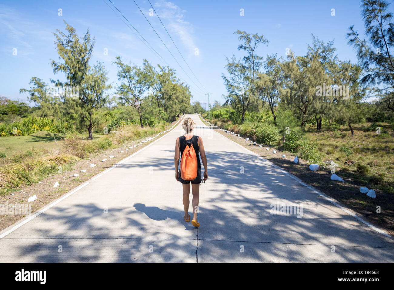 Woman walking in middle of rural road, Pagudpud, Ilocos Norte ...