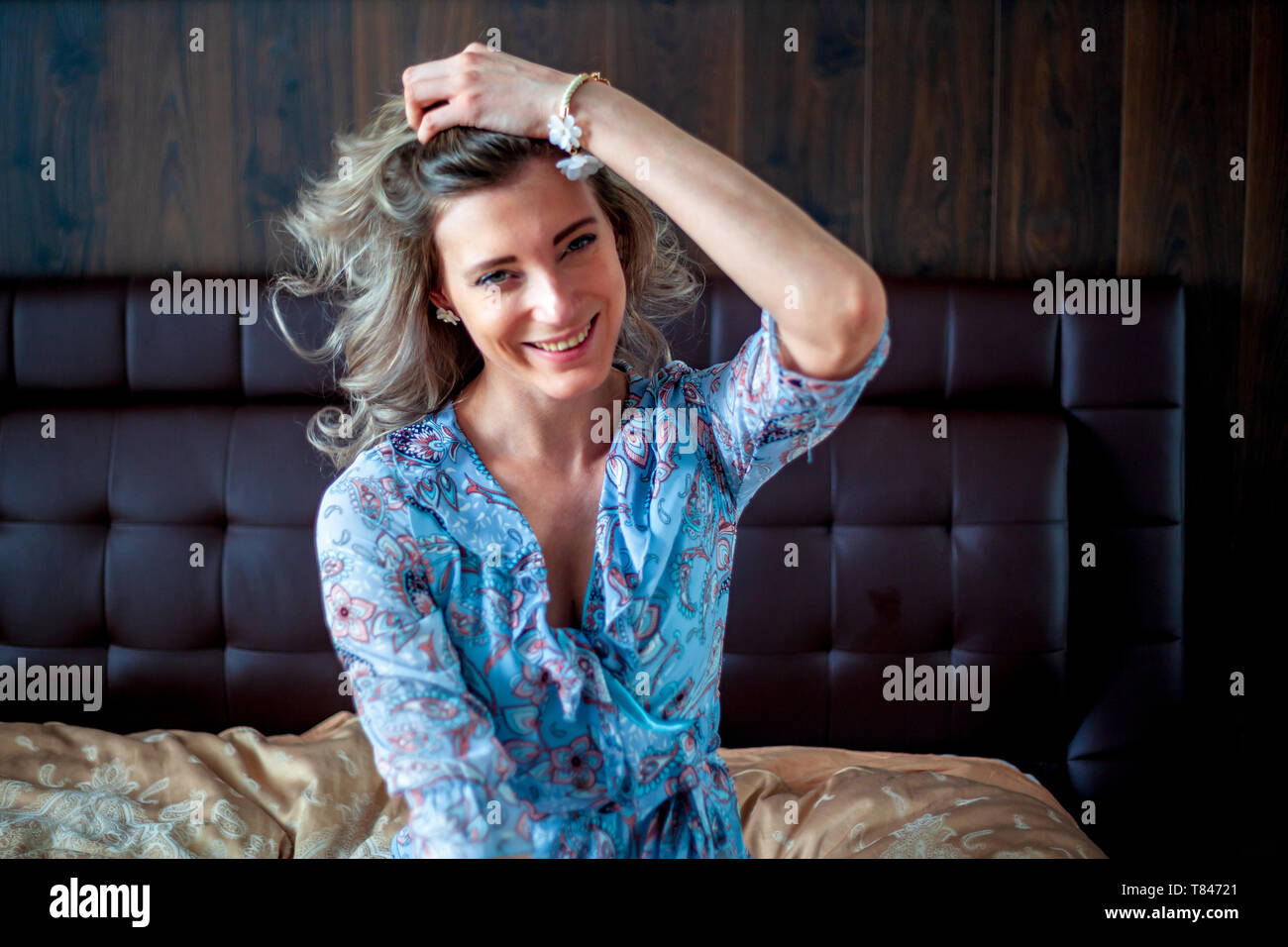 Woman running hand through hair on bed Stock Photo - Alamy
