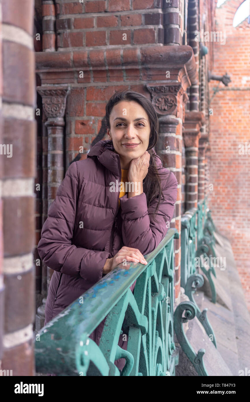 Woman leaning against railings of old building Stock Photo - Alamy