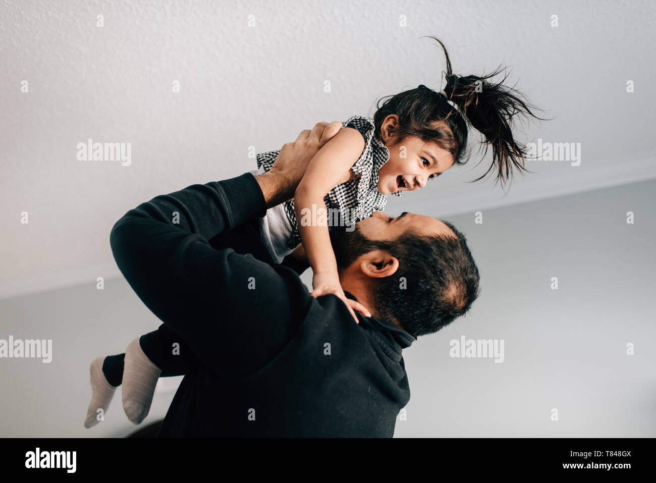 Girl being held up by father, side view Stock Photo - Alamy