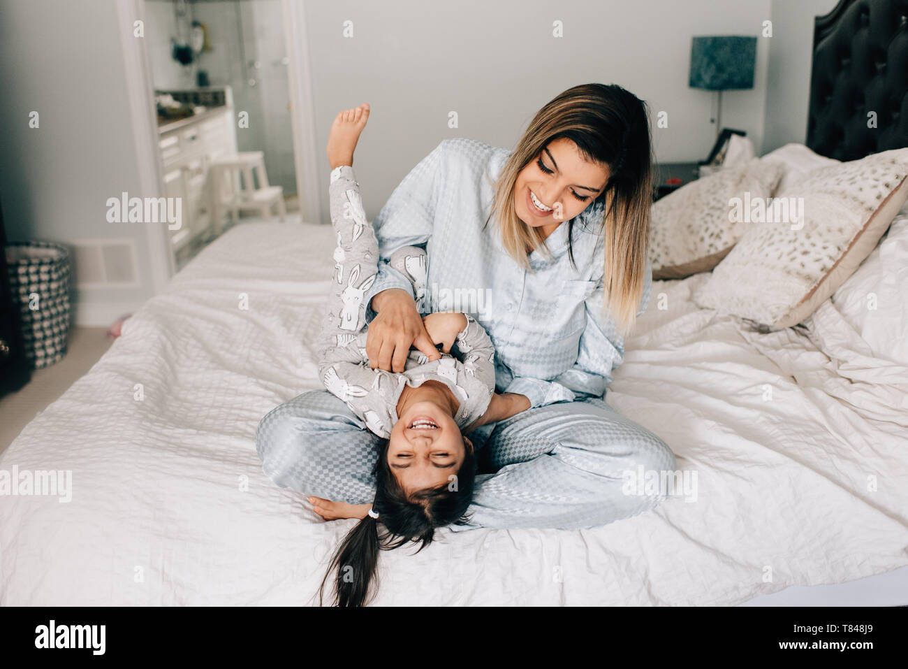 Girl being tickled by her mother on bed in morning Stock Photo - Alamy