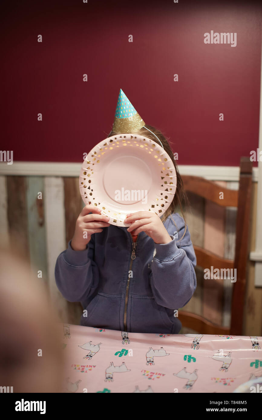 Birthday girl covering face with plate Stock Photo - Alamy