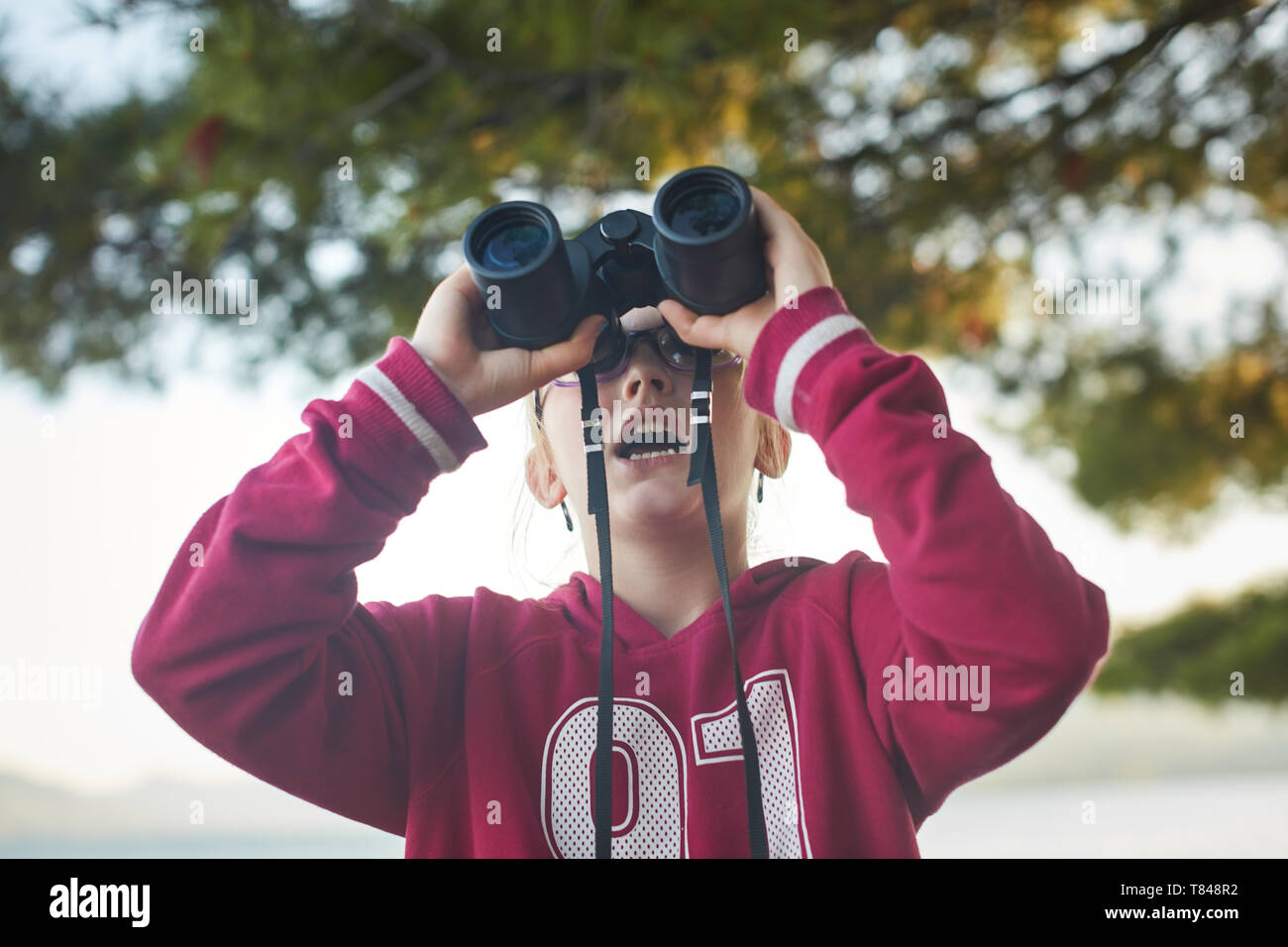 Girl looking up through binoculars Stock Photo - Alamy