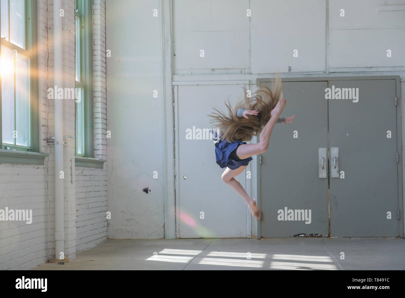Teenage girl with long brown hair leaping mid air in dance studio Stock ...