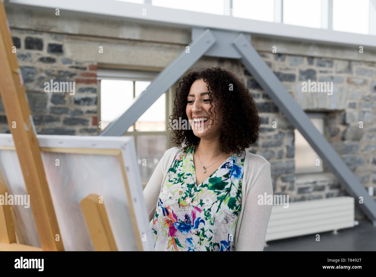 Young female painter laughing whilst painting canvas in studio Stock ...
