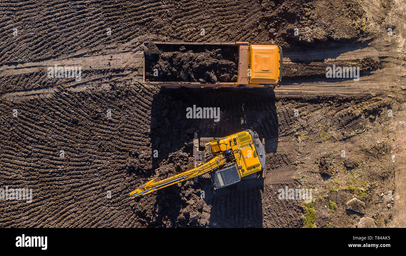 Aerial construction - top down view of an excavator and truck working ...